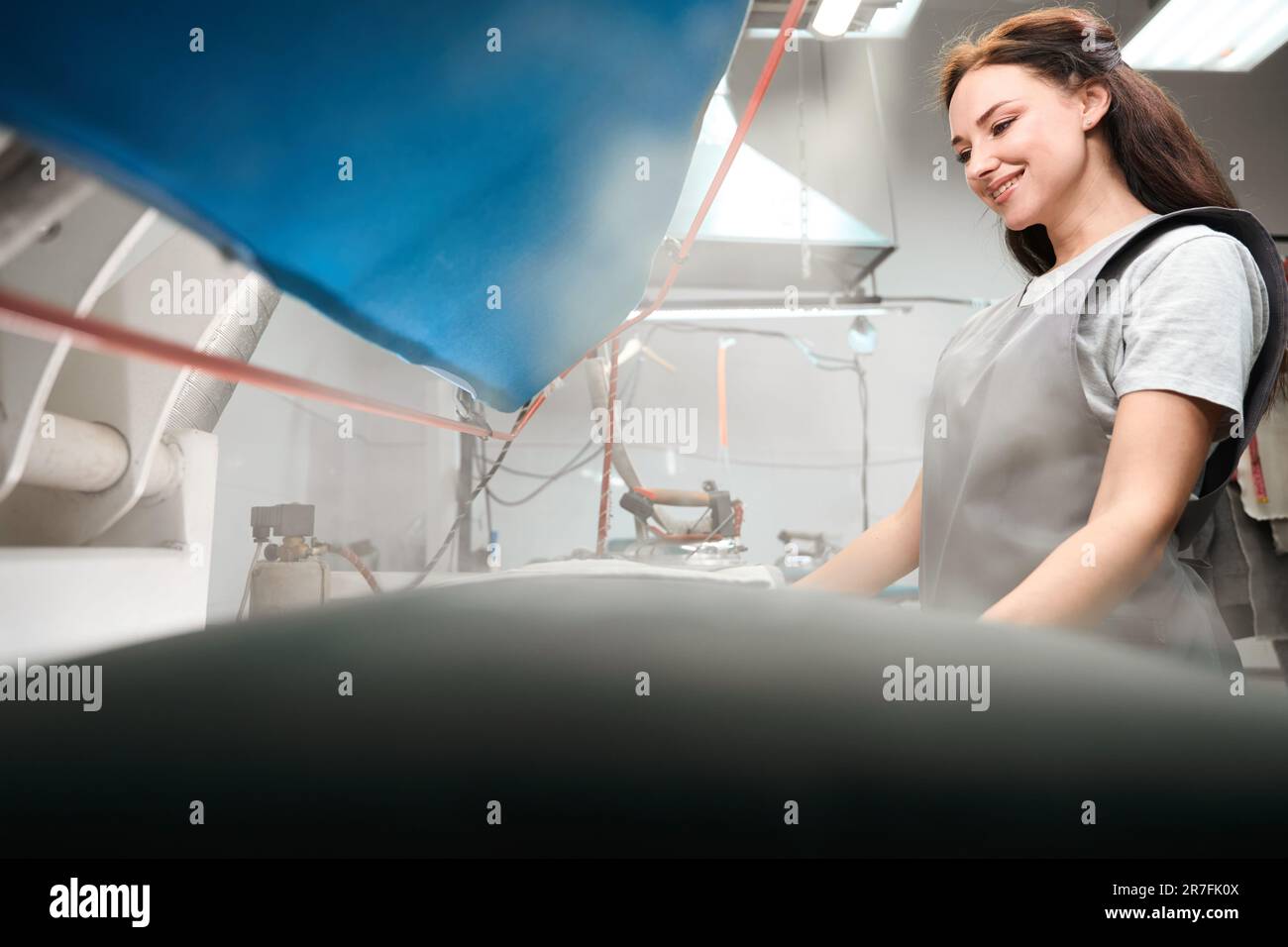 Laundry office worker drying and ironing clothes using steam press ...