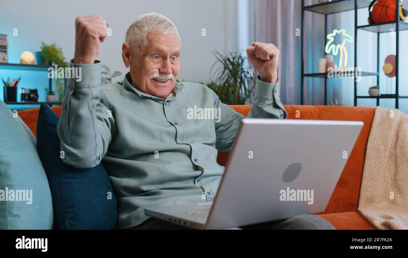 Oh my God Wow. Surprised senior man using laptop computer, receive good ...