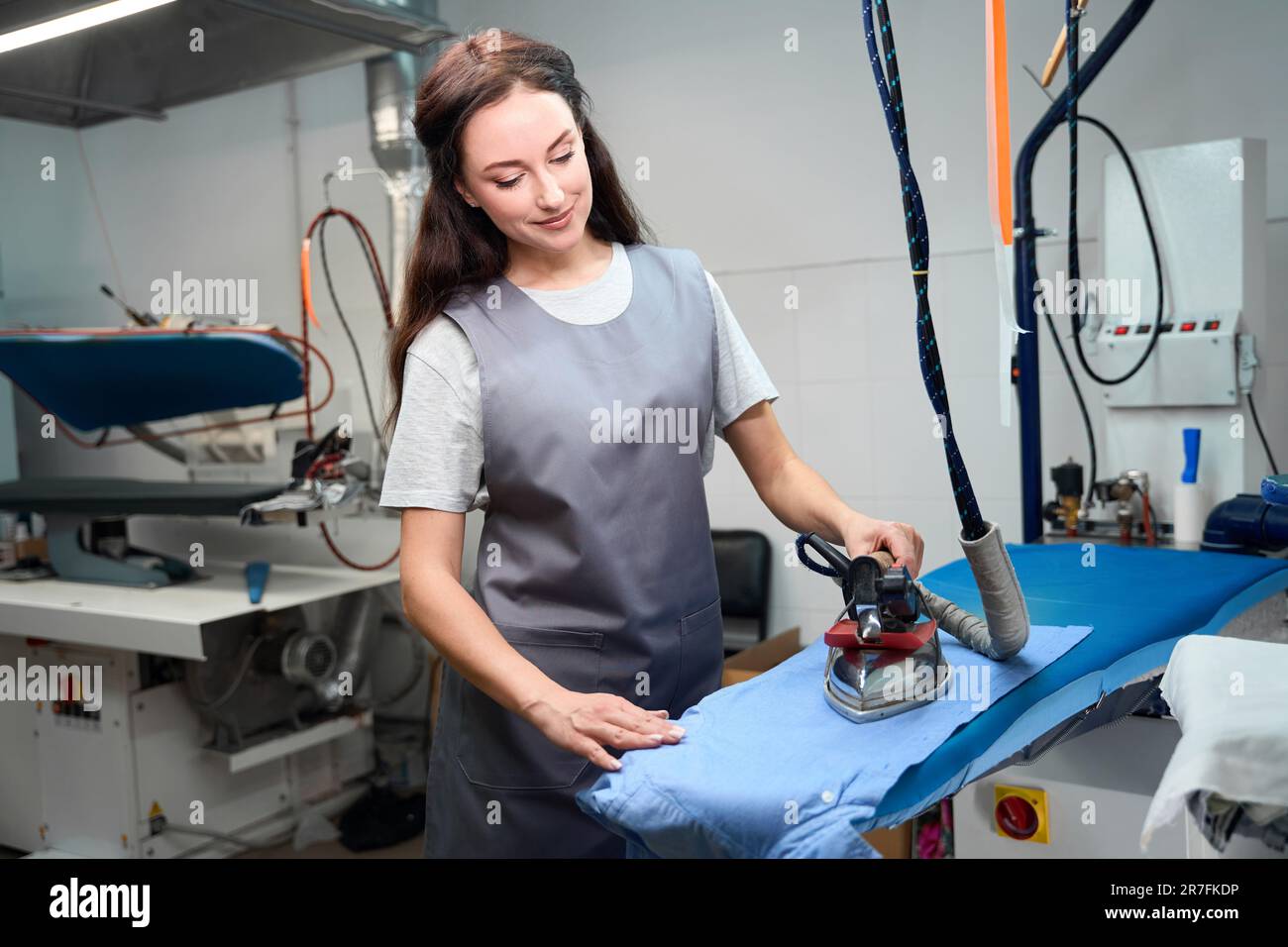 Woman washing house worker carefully ironing shirt on ironing board ...