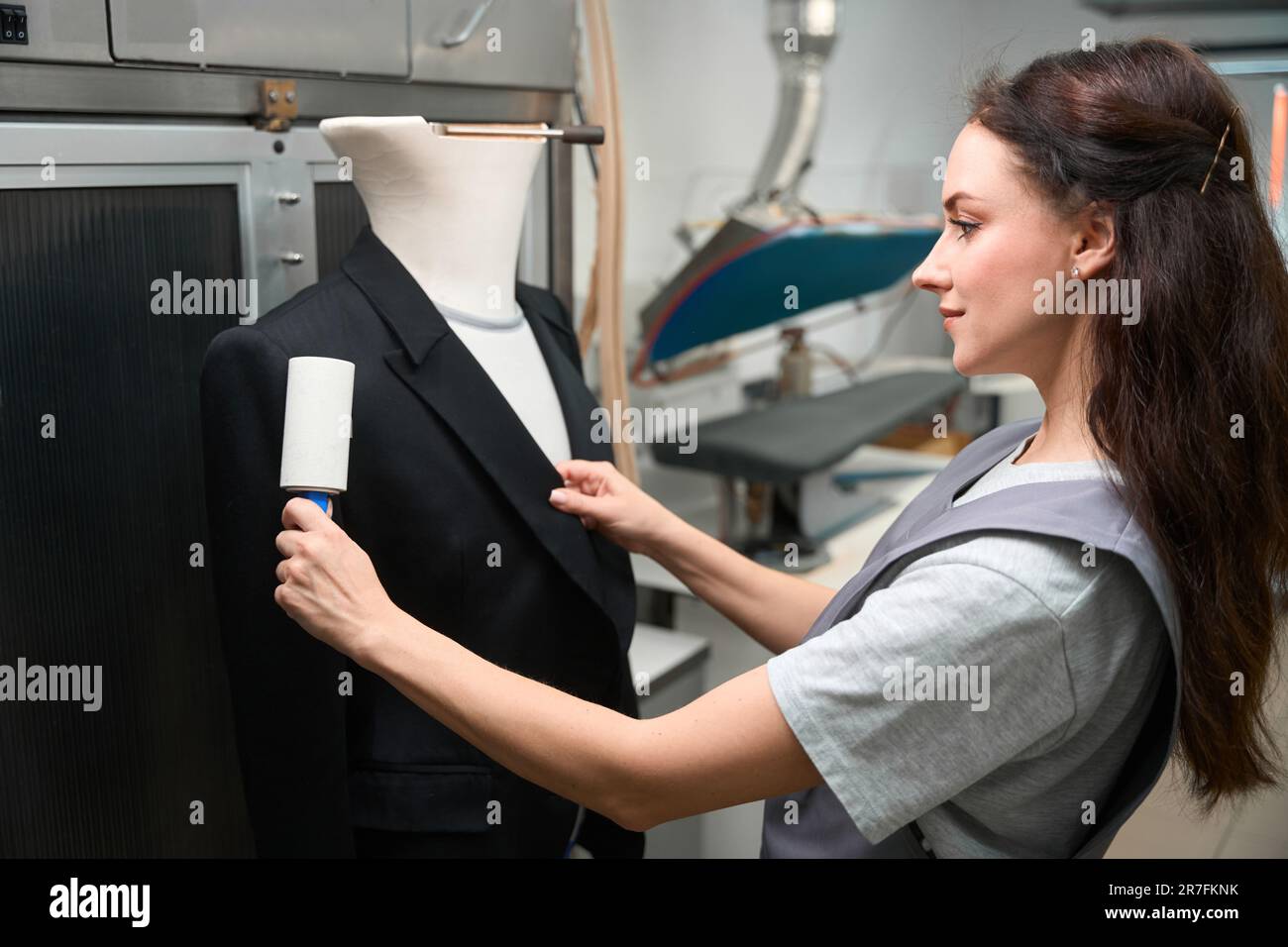 Woman dry-cleaning office worker cleaning jacket with sticky lint ...