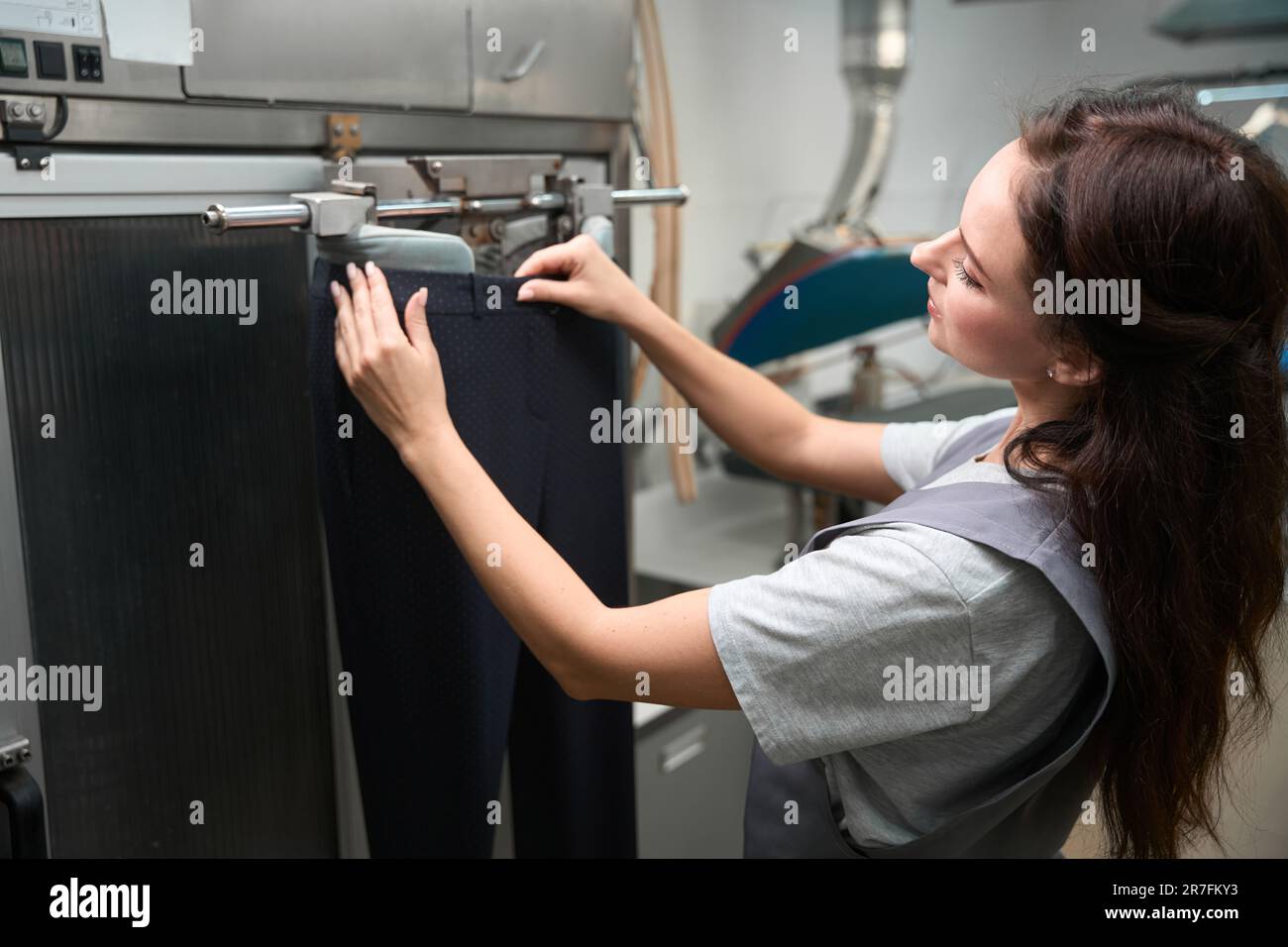 Dry-cleaning service operator wearing pants on automatic ironing ...