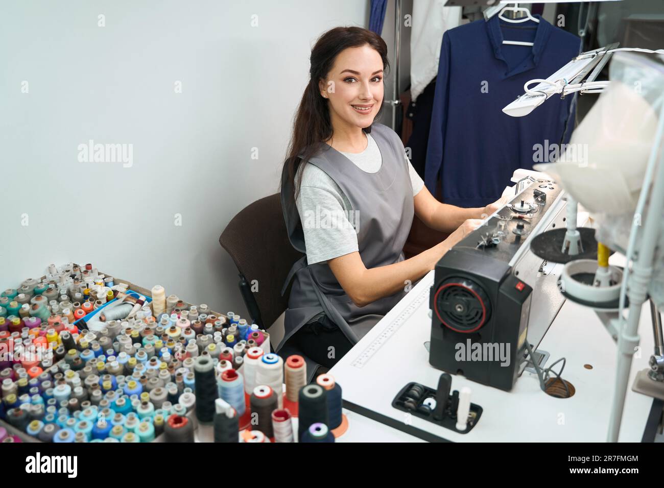Tailor sitting at sewing machine, processing clothes after dry cleaning ...