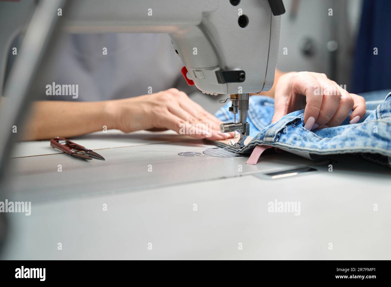 Seamstress sewing tags to clothes on sewing machine Stock Photo - Alamy