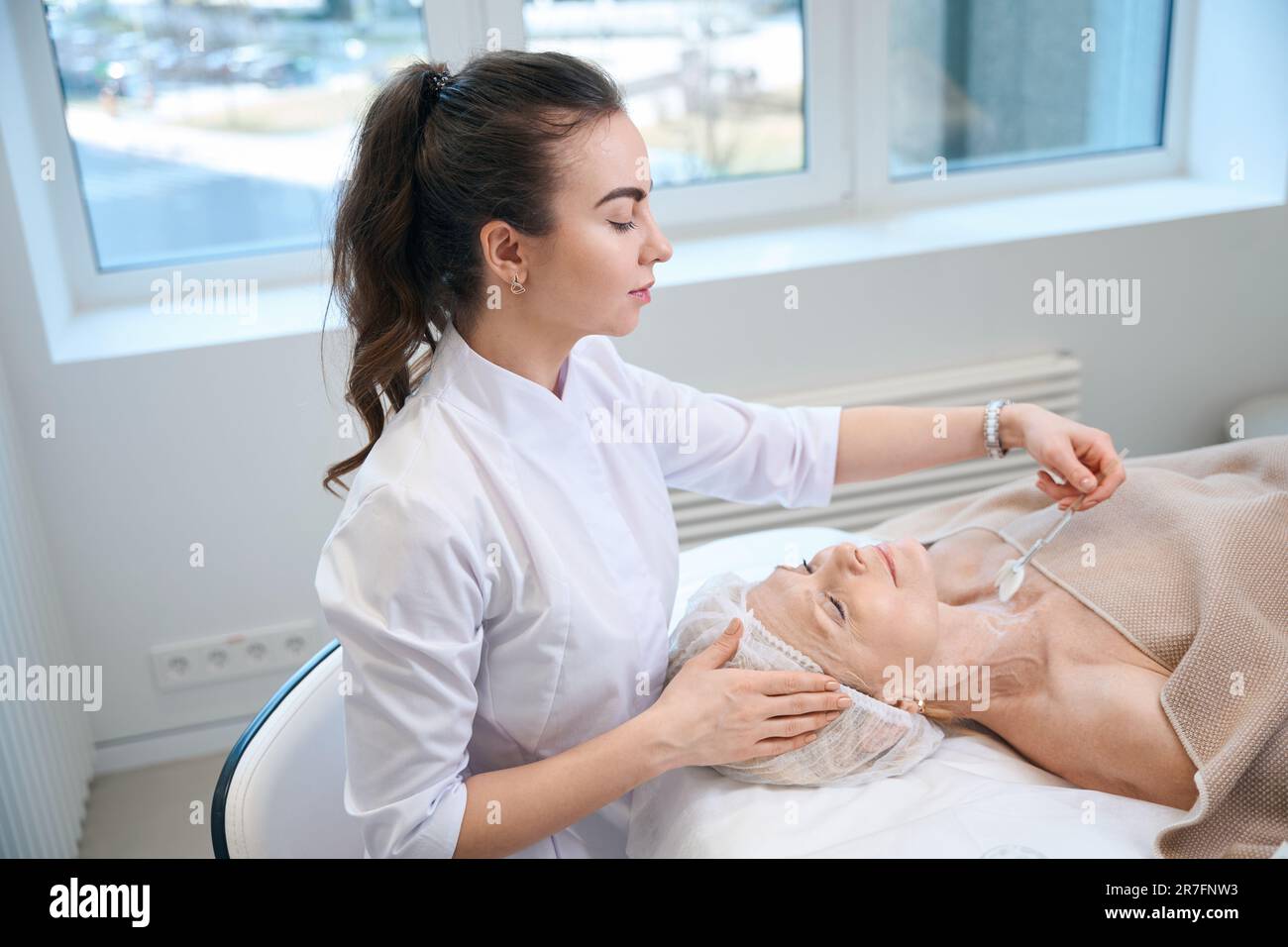 Beautician performing beauty neck procedure for adult lady Stock Photo ...