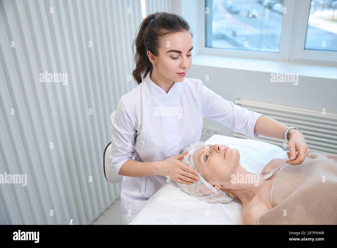 Female beautician performing beauty neck procedure for adult lady Stock ...