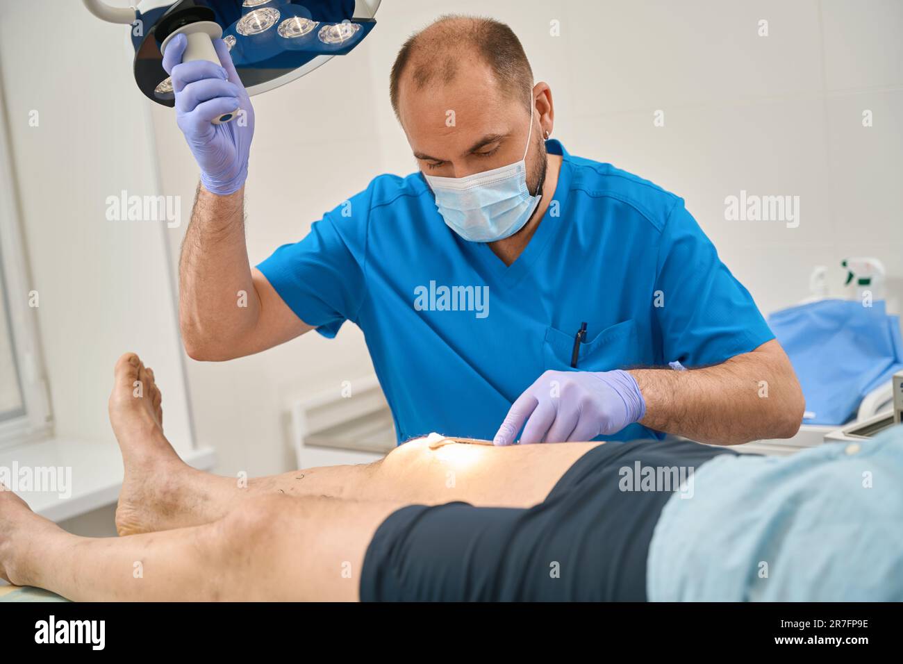 Doctor correcting shadowless lamp by directing light to right place ...
