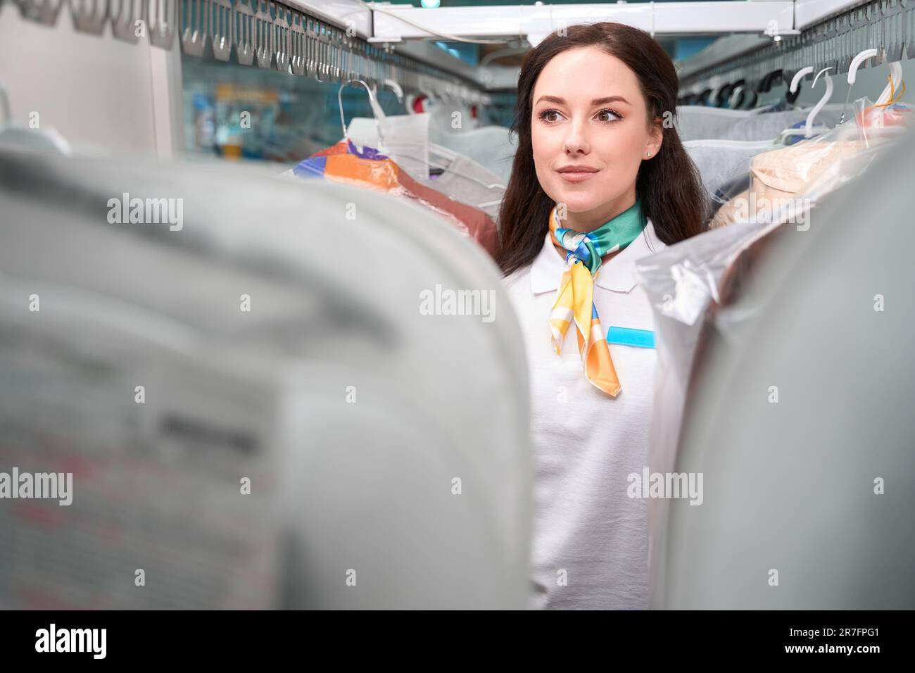 Woman laundry office administrator moving along racks with clothes on ...