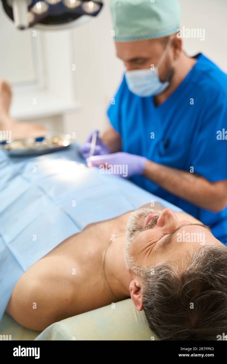 Man on operating table who is injected by doctor Stock Photo - Alamy
