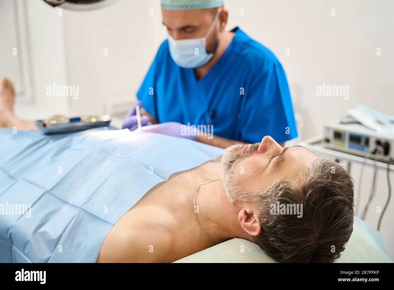 Man on operating table to whom doctor injects with syringe Stock Photo ...