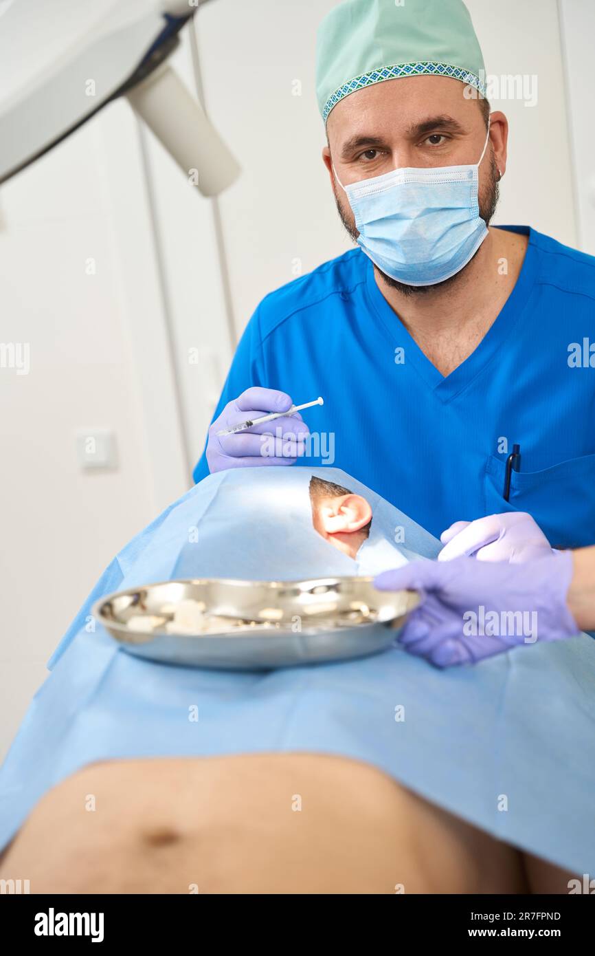 Surgeon with syringe for injections stands near head of patient Stock ...