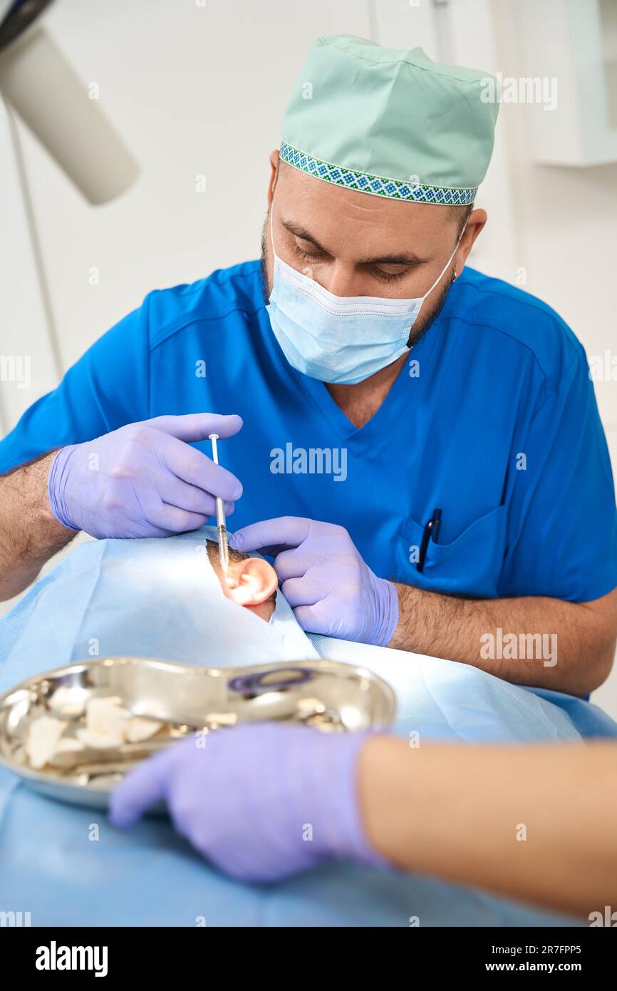 Doctor in operating room who makes injection into man ear Stock Photo ...