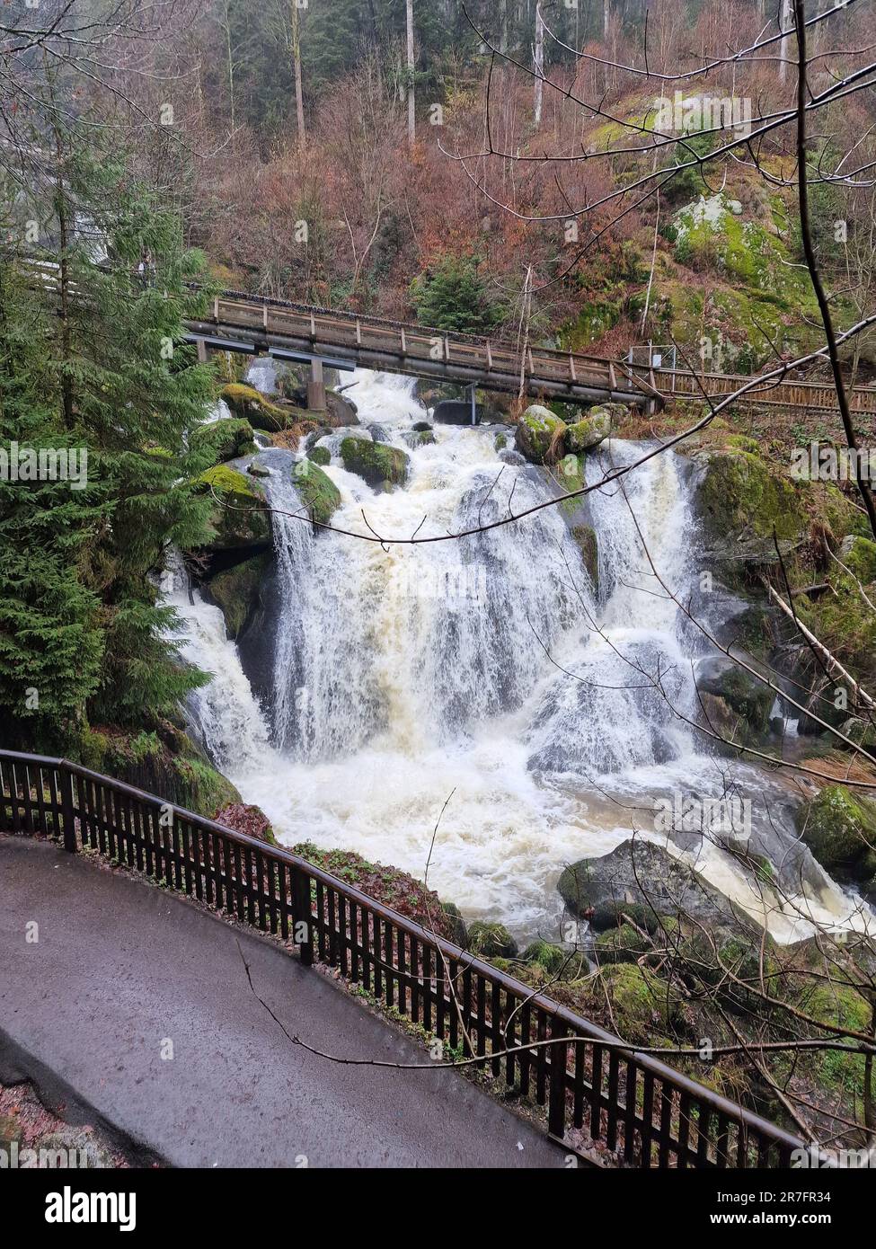 A scenic landscape of a bridge arching over a small waterfall Stock ...