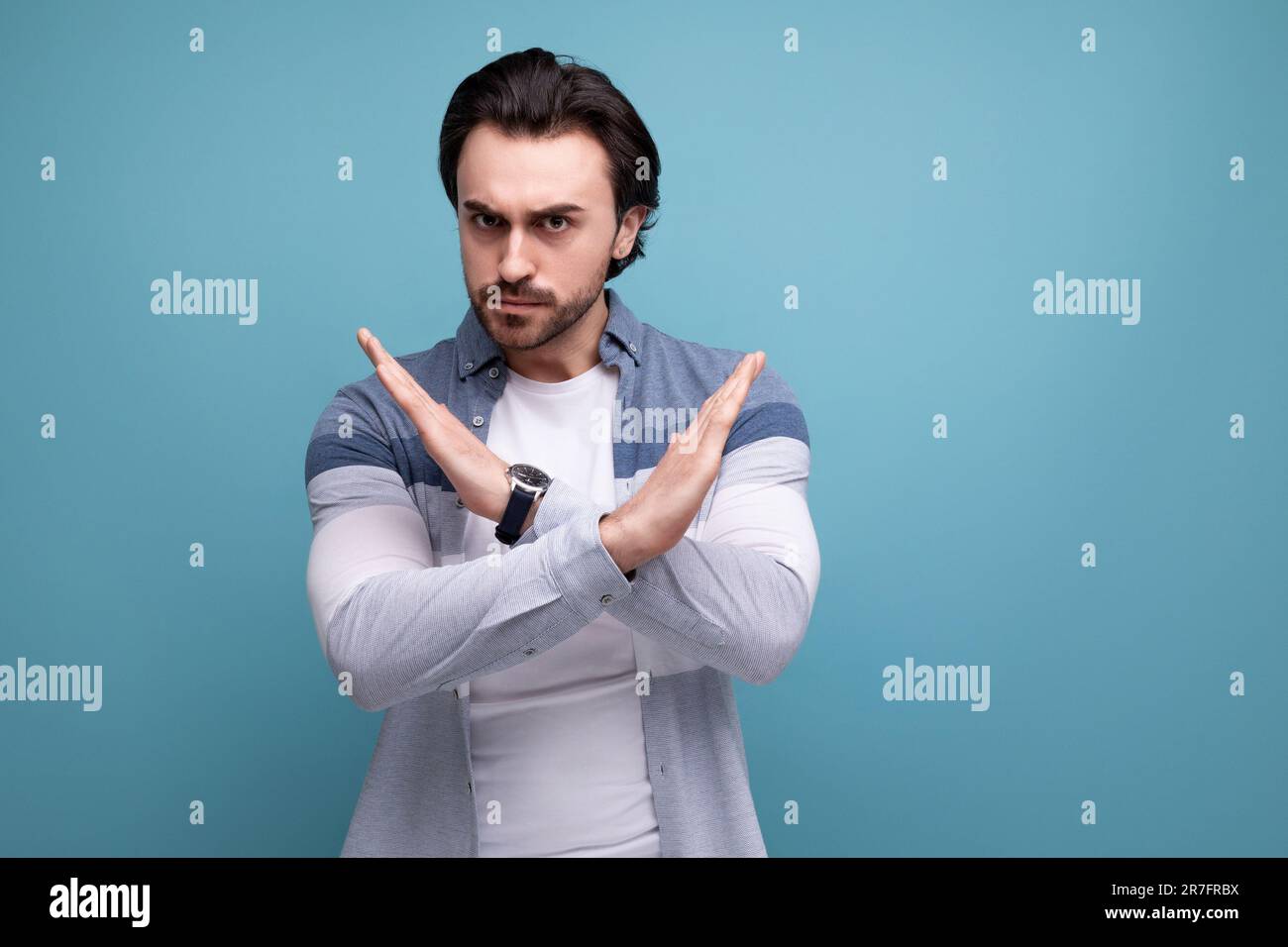 young brunette man in model appearance with crossed arms on studio ...