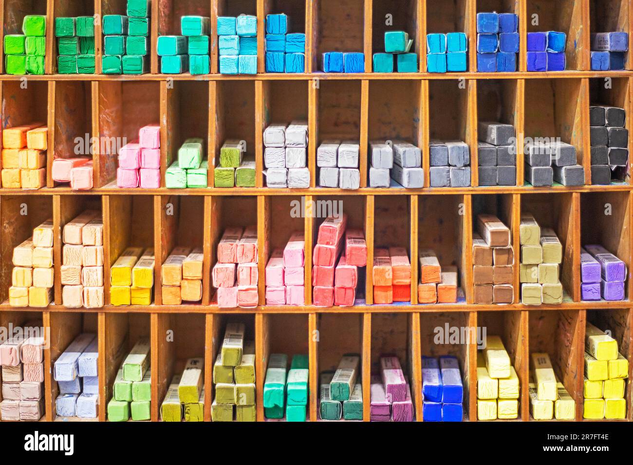 multi-colored dry pastel crayons laid out on shelves. Art materials ...