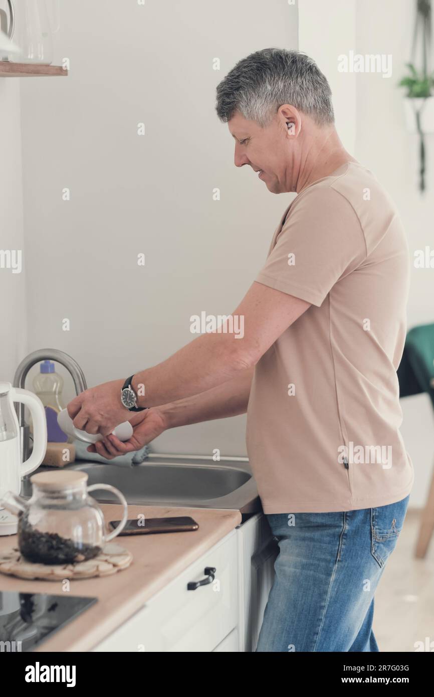 mature man with grey hair washing dishes. housekeeping and cleaning ...