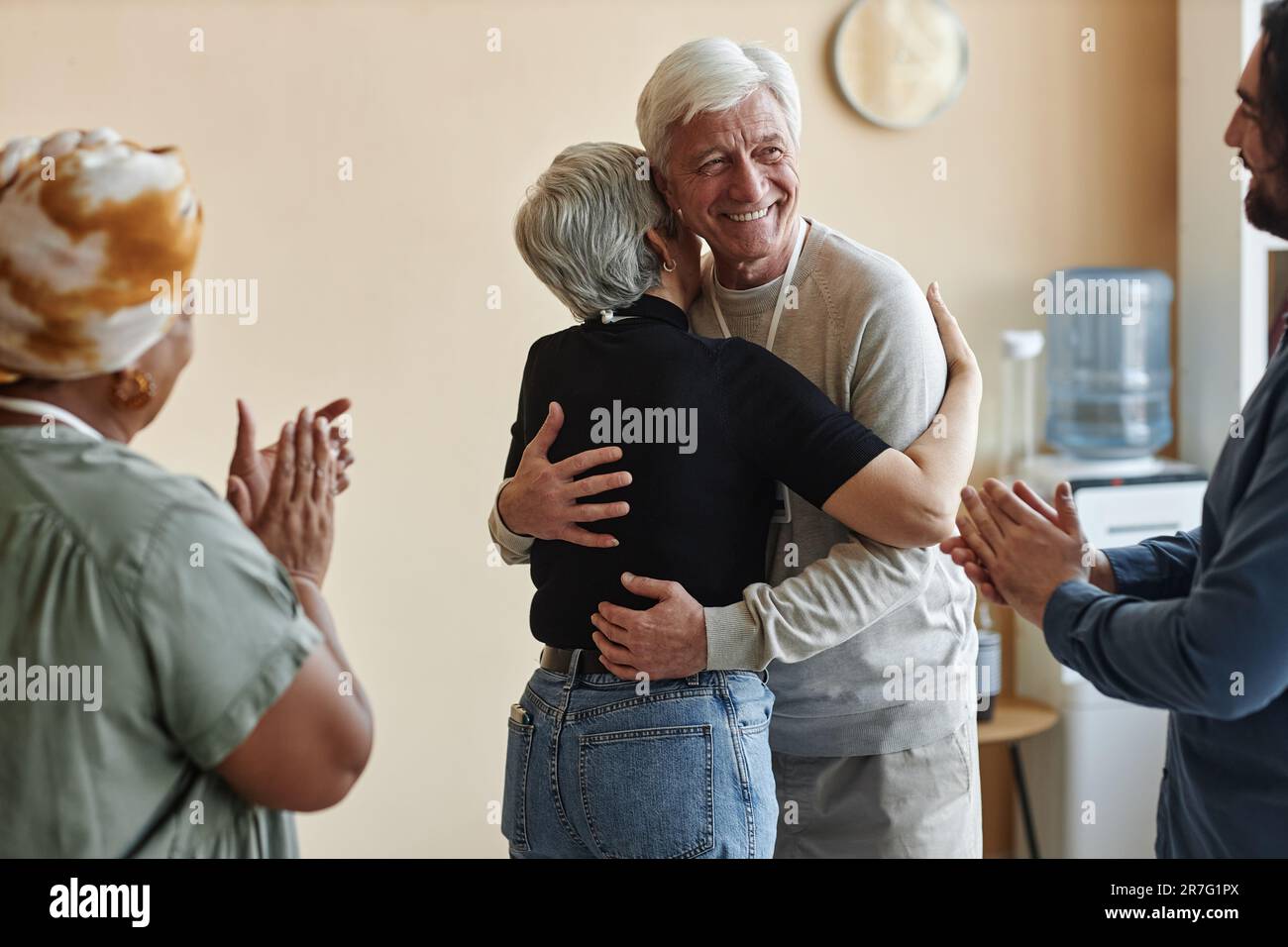 Cheerful group of elderly people applauding and embracing in support ...