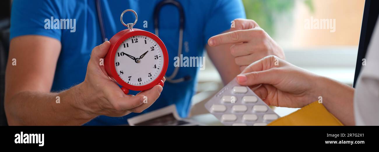 Doctor is holding alarm clock and female patient with pills Stock Photo ...