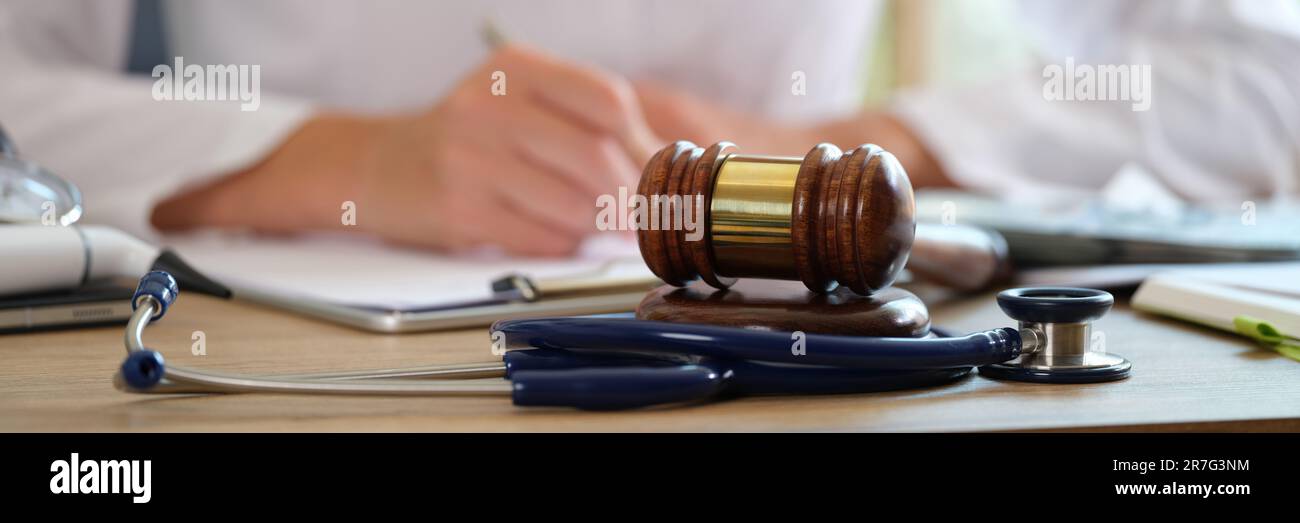 Court gavel with stethoscope on a table in background doctor writes ...