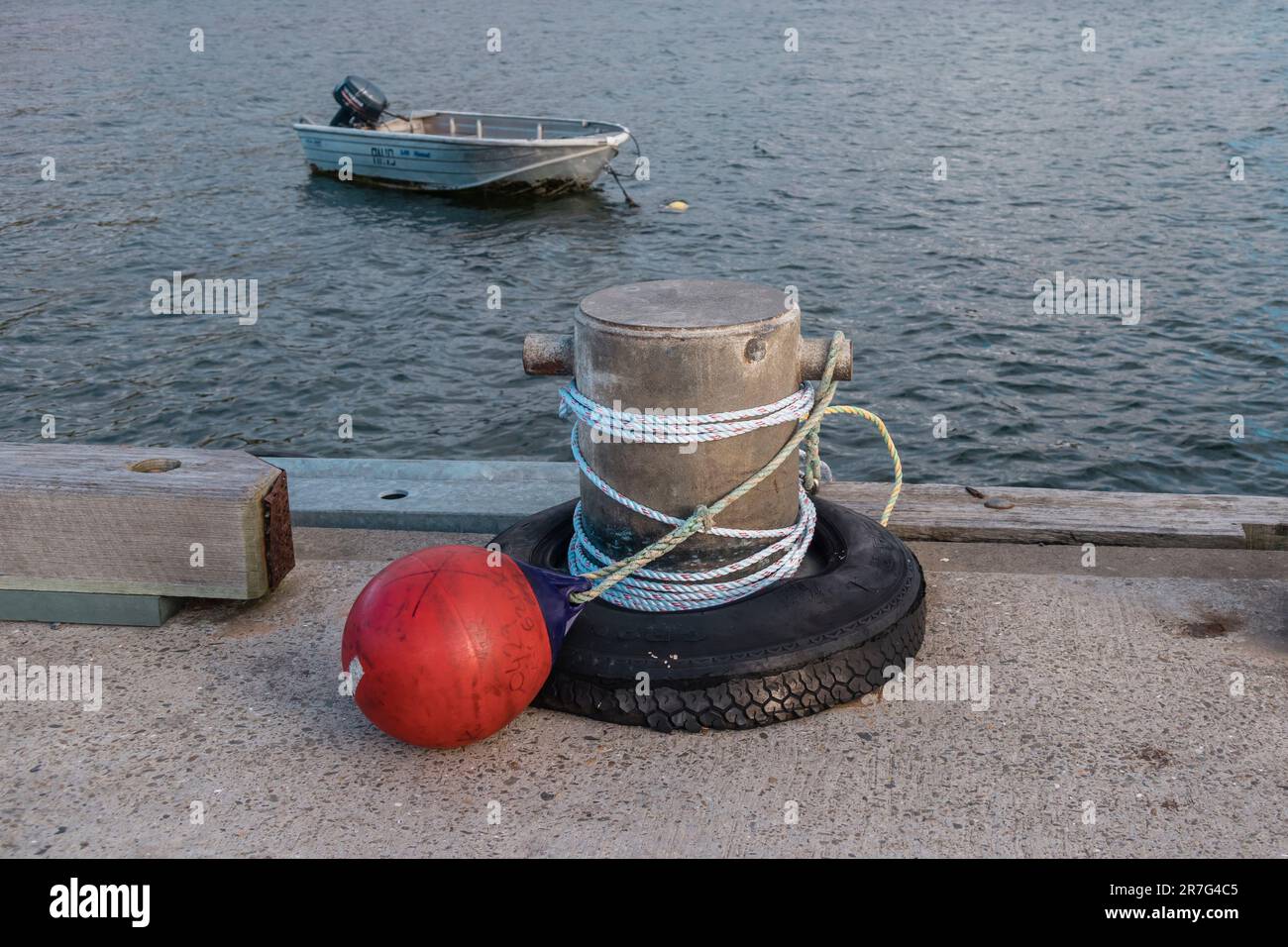 Photograph of white rope wrapped around a steel boat bollard with a red ...