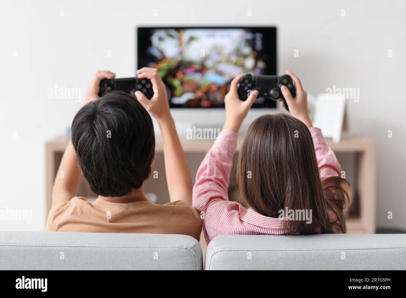 Little children playing video game at home, back view Stock Photo - Alamy