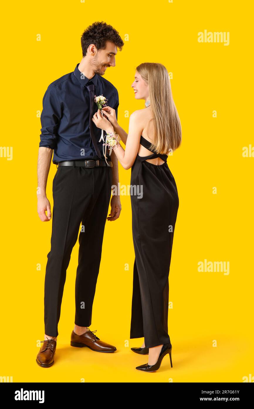 Beautiful prom couple pinning boutonniere on yellow background Stock ...