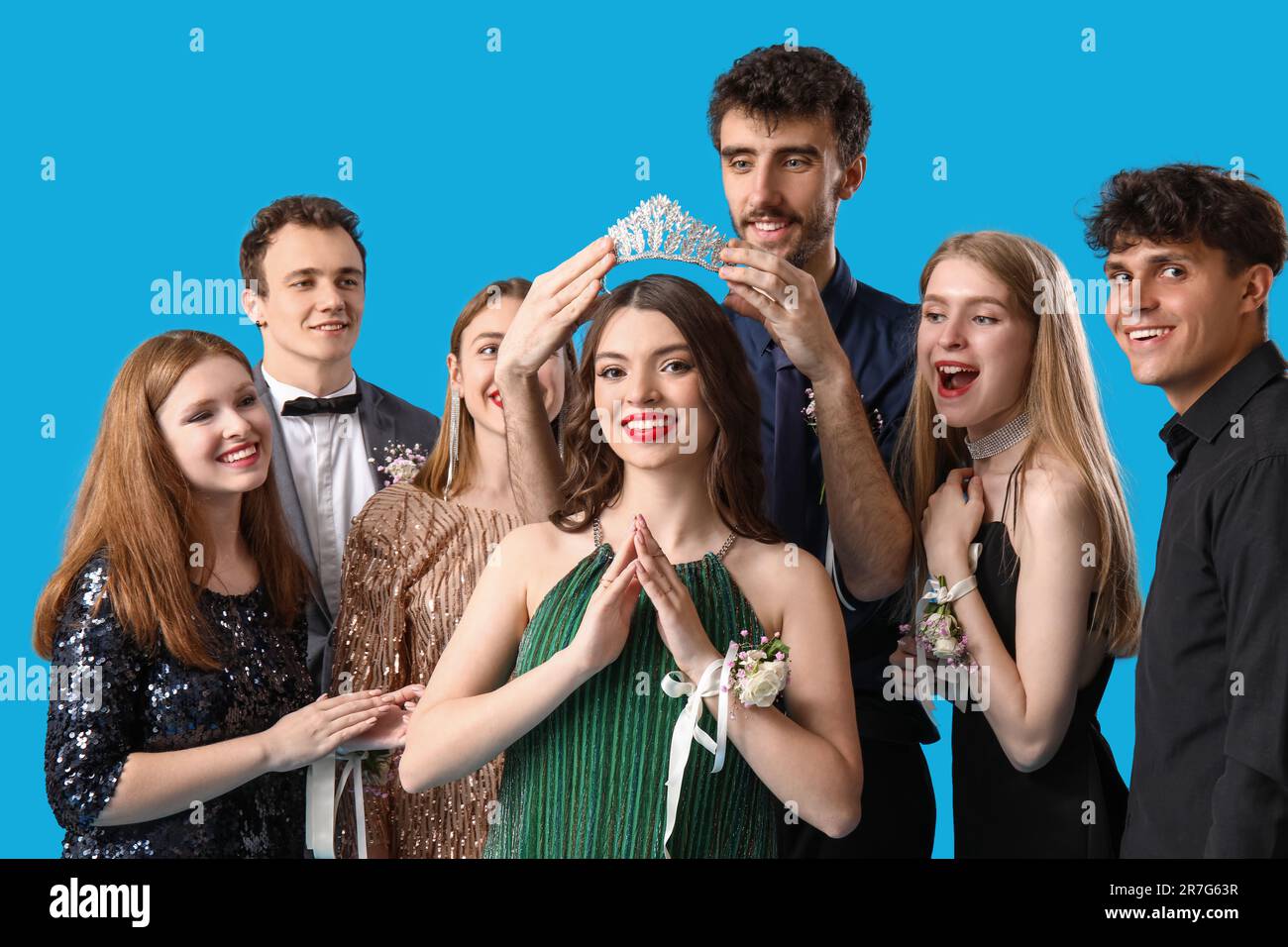 Young people crowning prom queen on blue background Stock Photo - Alamy