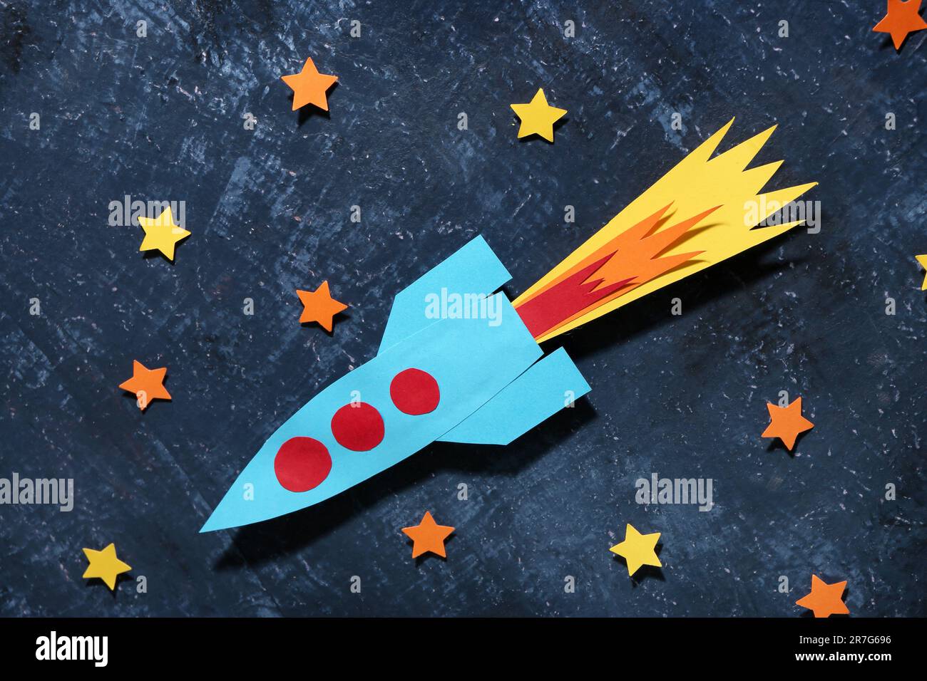 Blue paper rocket with stars on dark grunge background Stock Photo - Alamy