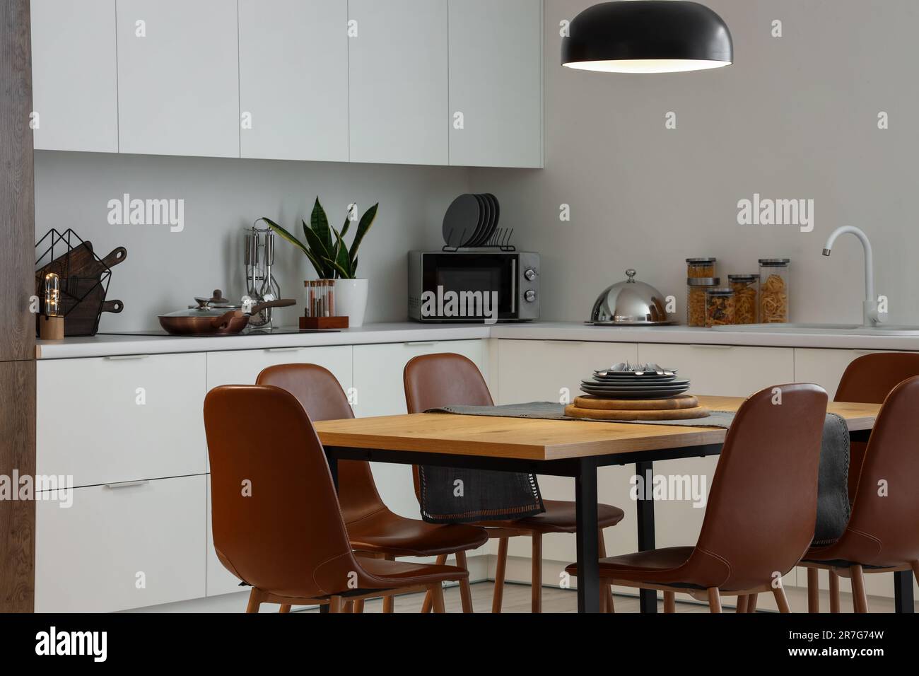 Interior of modern kitchen with dining table and glowing lamp Stock ...