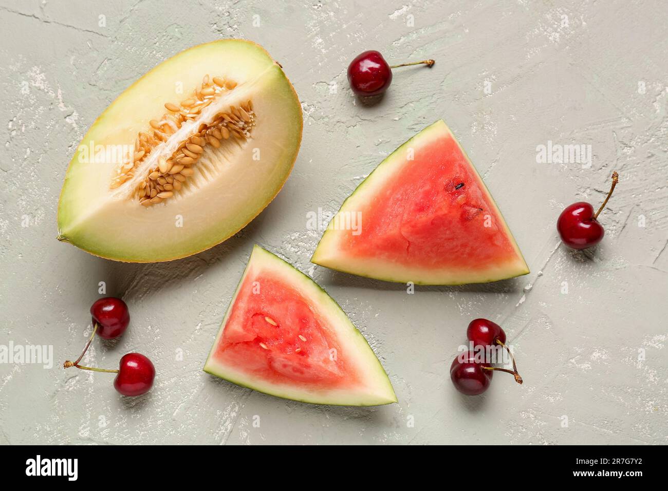 Pieces of fresh watermelon, melon and cherries on grey background Stock ...