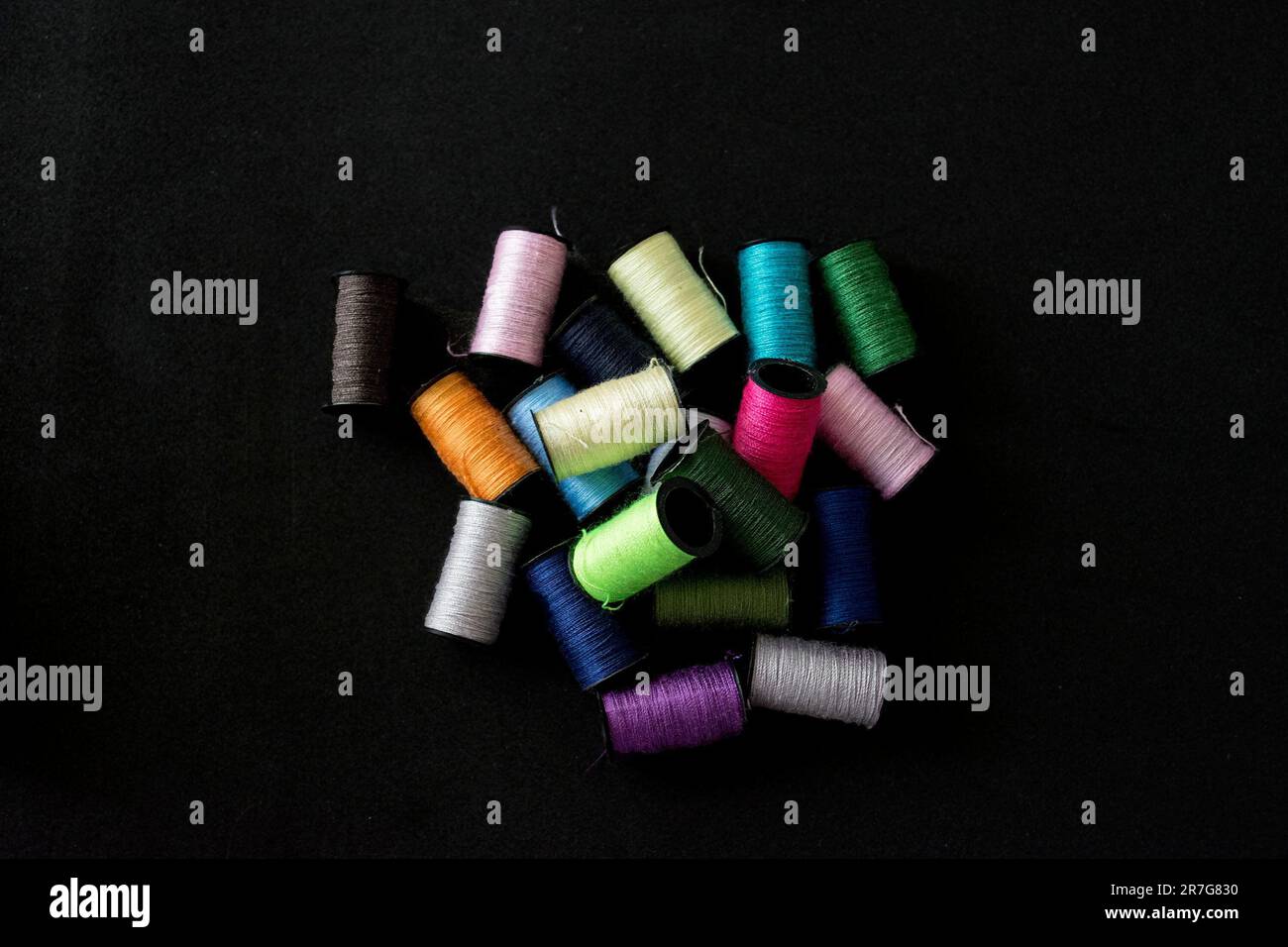 A pile of various colored rolls of thread on a black background Stock ...