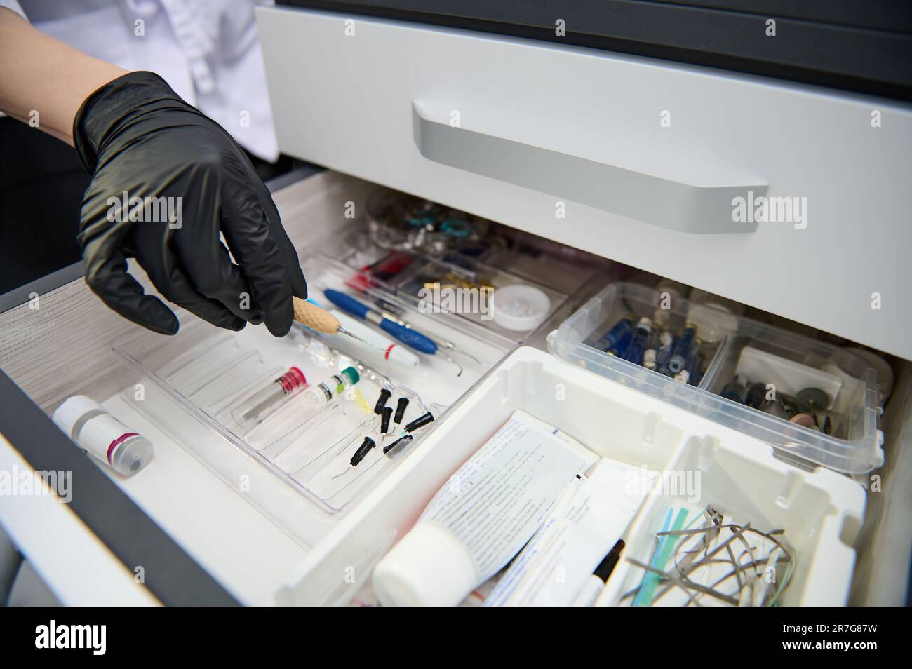 Close-up gloved hand of dentist taking out dental tool form the drawer ...