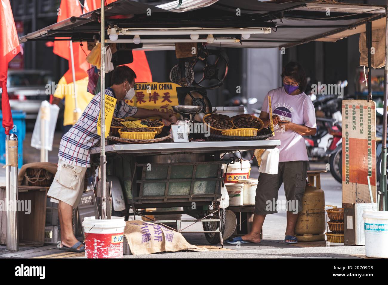 Two adult males in casual attire standing at a street-side food vendor ...