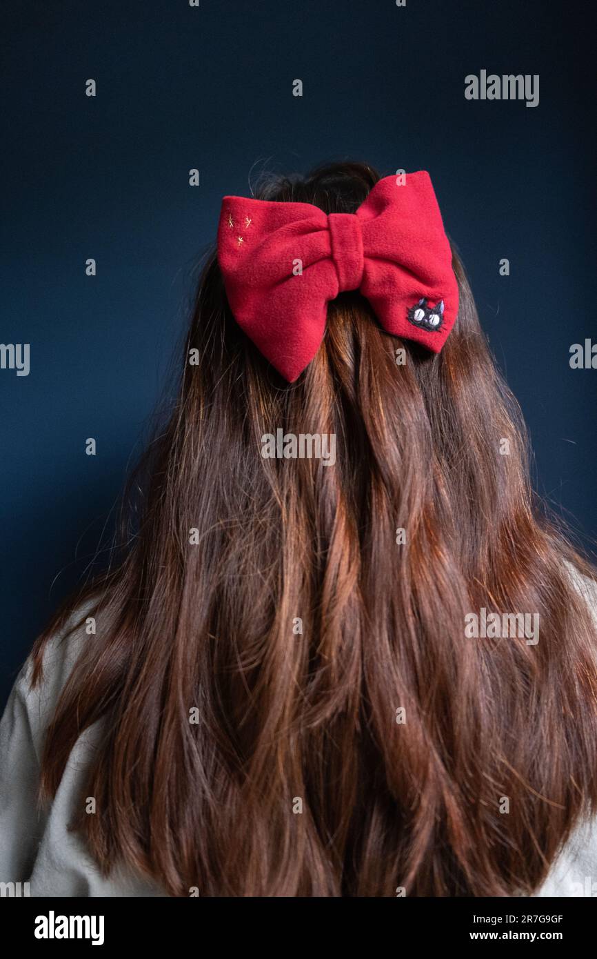 An attractive young woman with auburn hair, wearing a red bow, posing ...