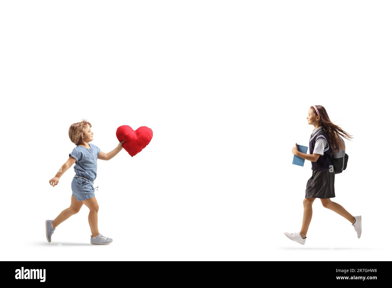 Little girl carrying a red heart and running to meet her sister ...