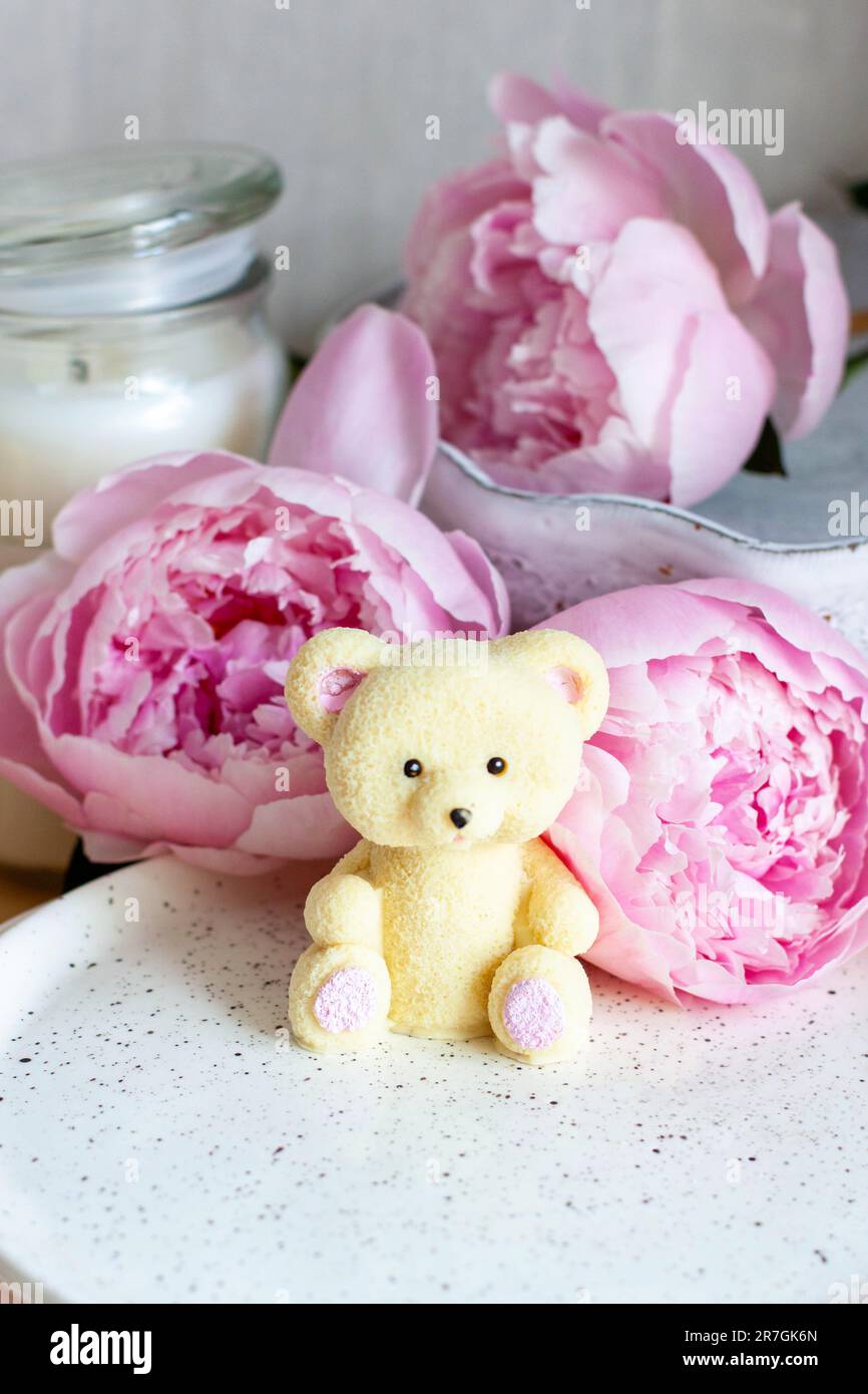 Cute edible teddy bear toy made of white chocolate with fresh peonies ...