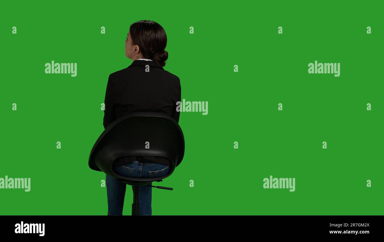 Back view of corporate worker sitting on chair and waiting on camera ...