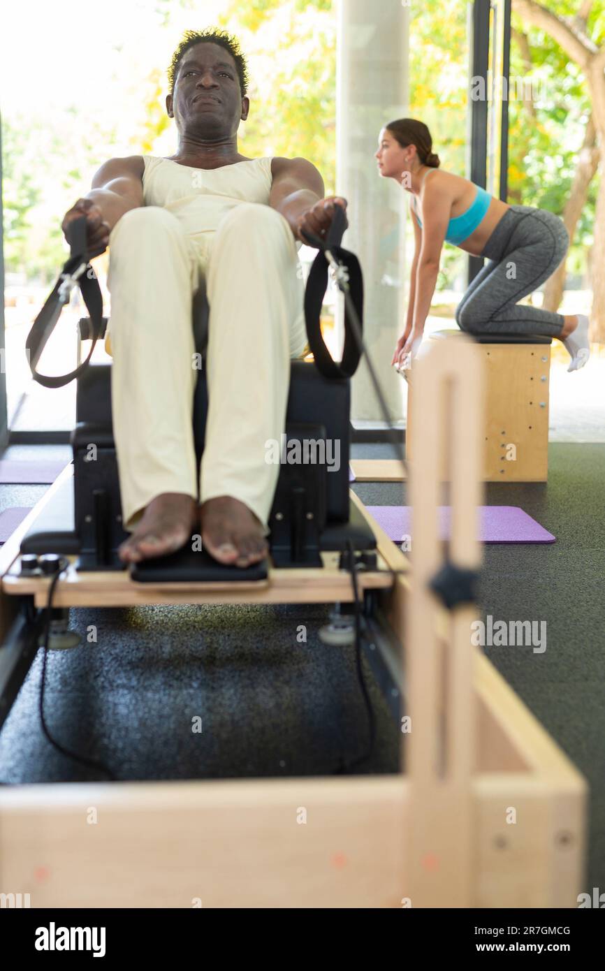 Man doing exercises on pilates reformer Stock Photo - Alamy