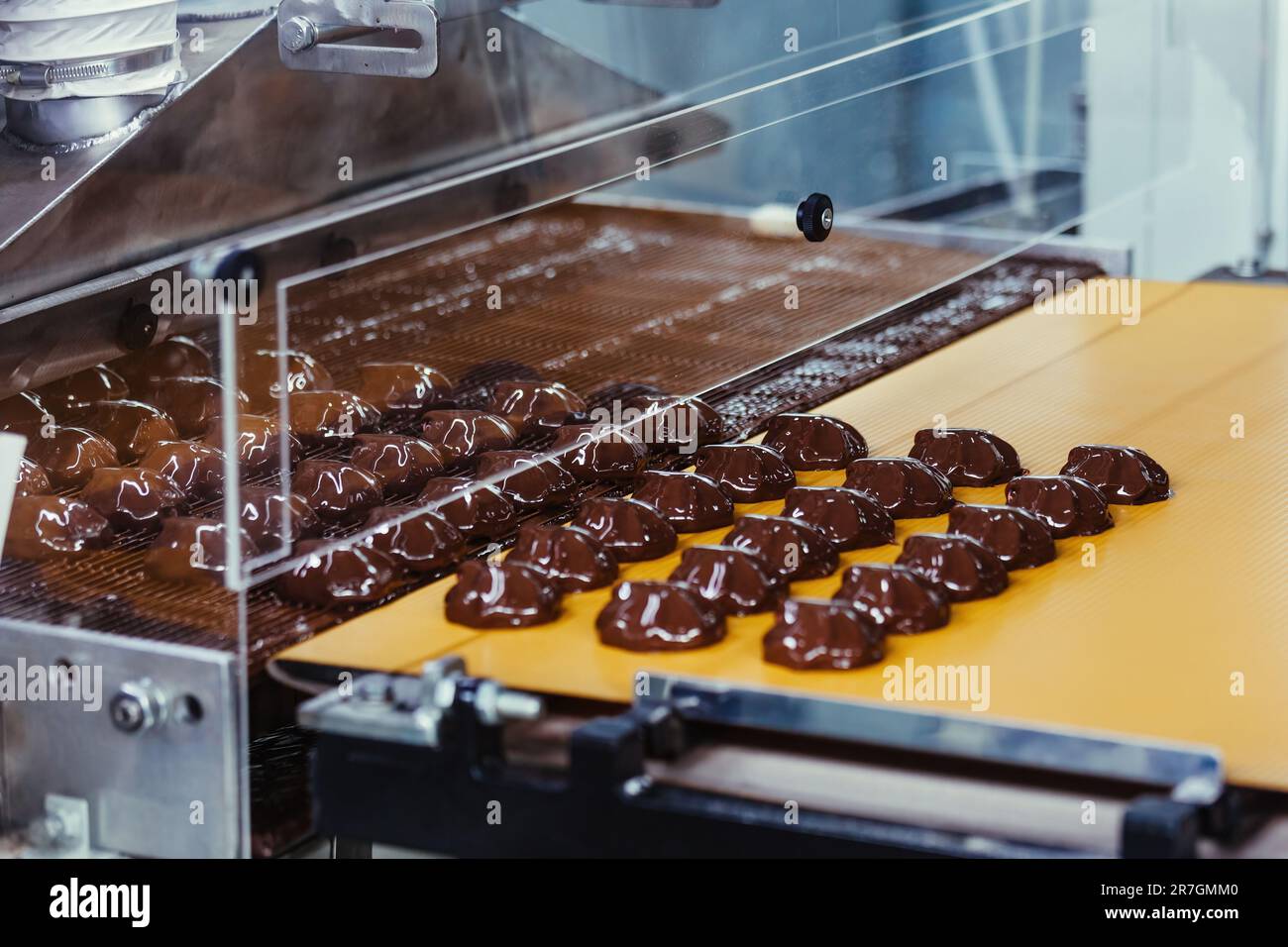 Process of chocolate glazing zephyrs in confectionery on conveyor machine. Marshmallow ...