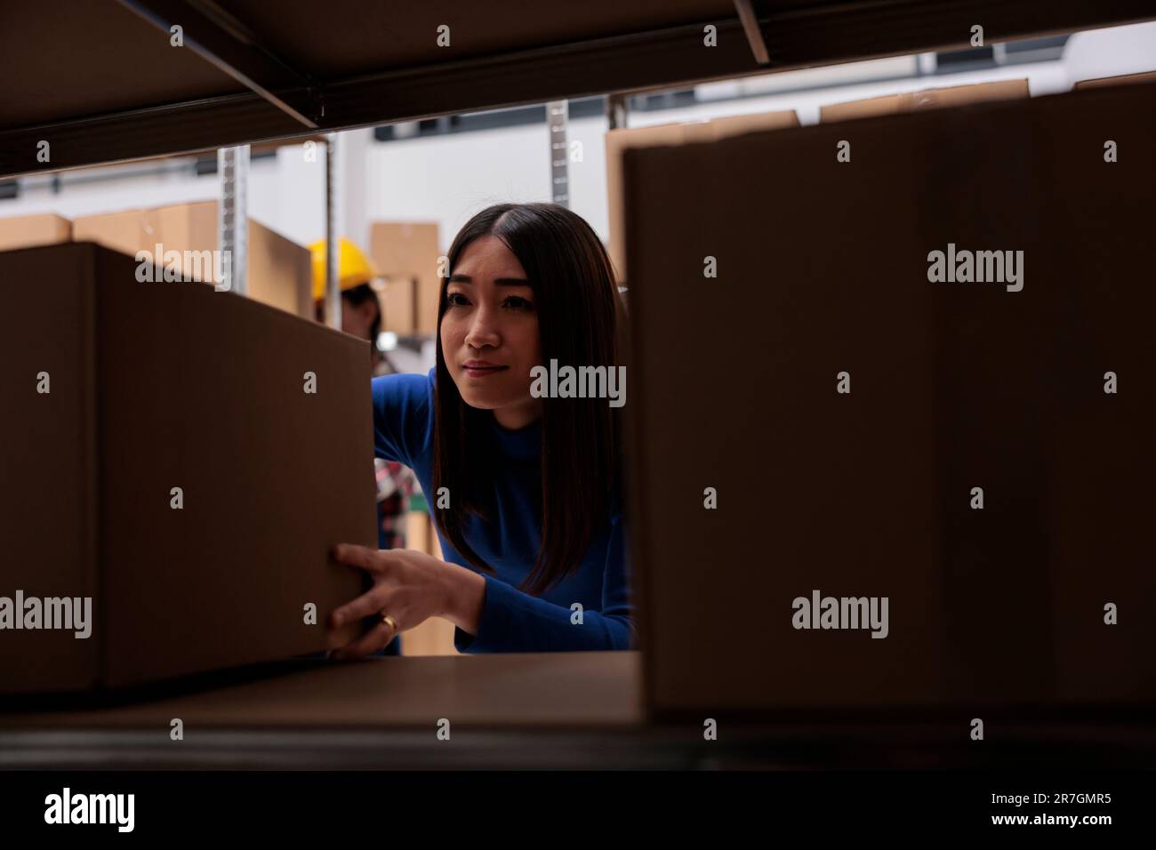 Distribution center worker taking cardboard box from rack to prepare ...