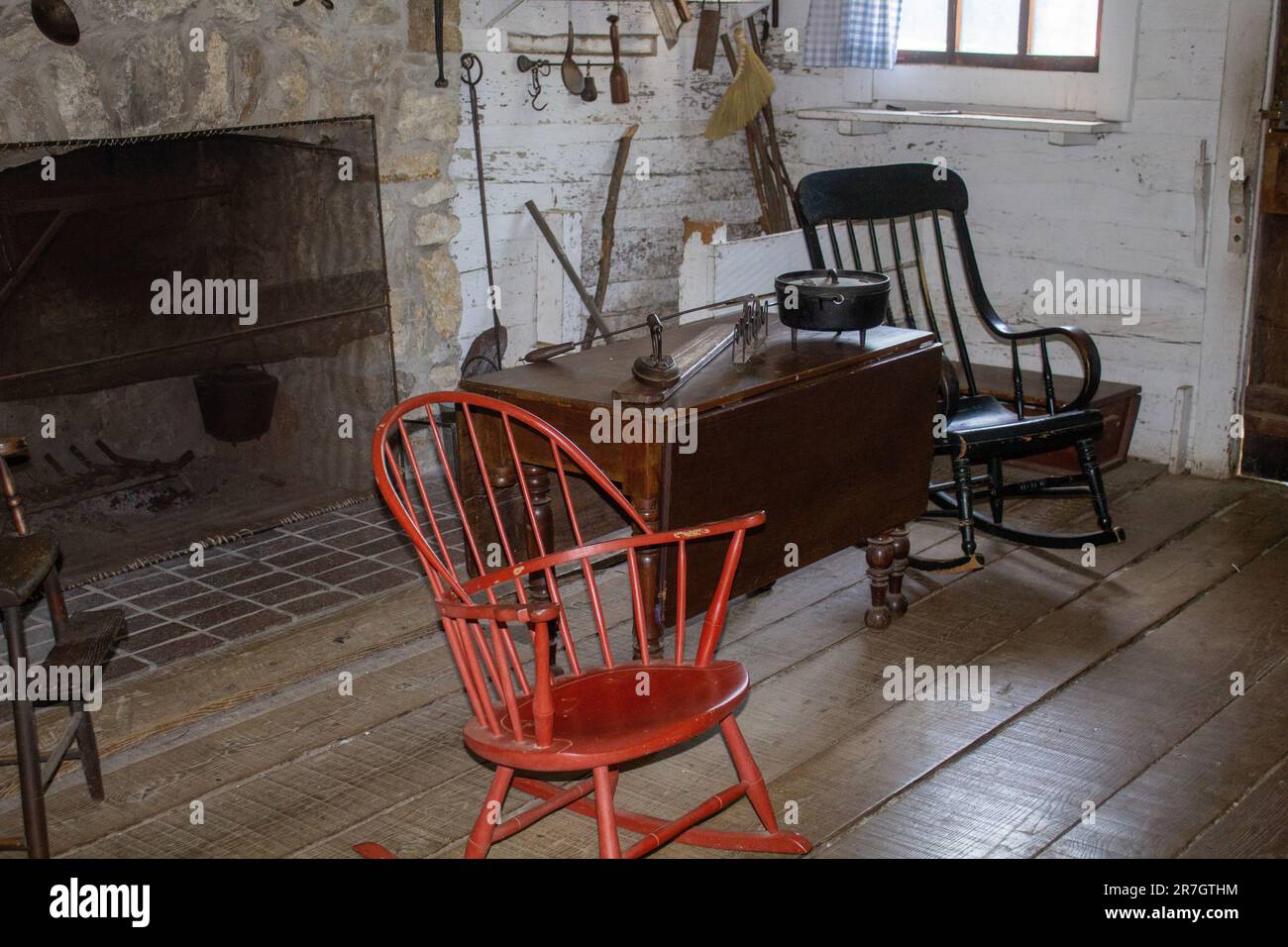 An interior of a traditional 1800s log cabin featuring red and black ...