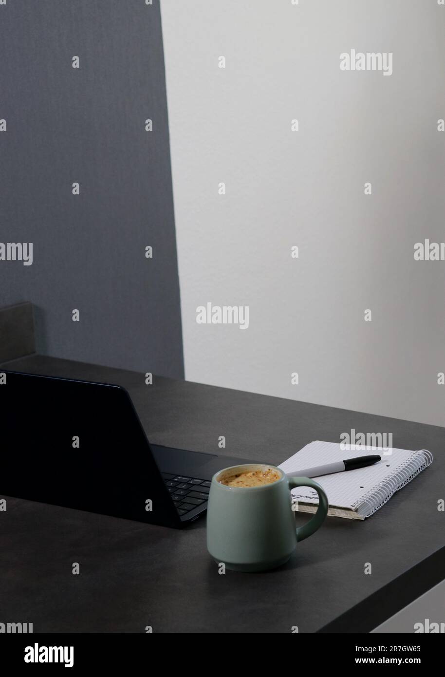 Workspace with green cup of coffee, notebook and black laptop computer ...