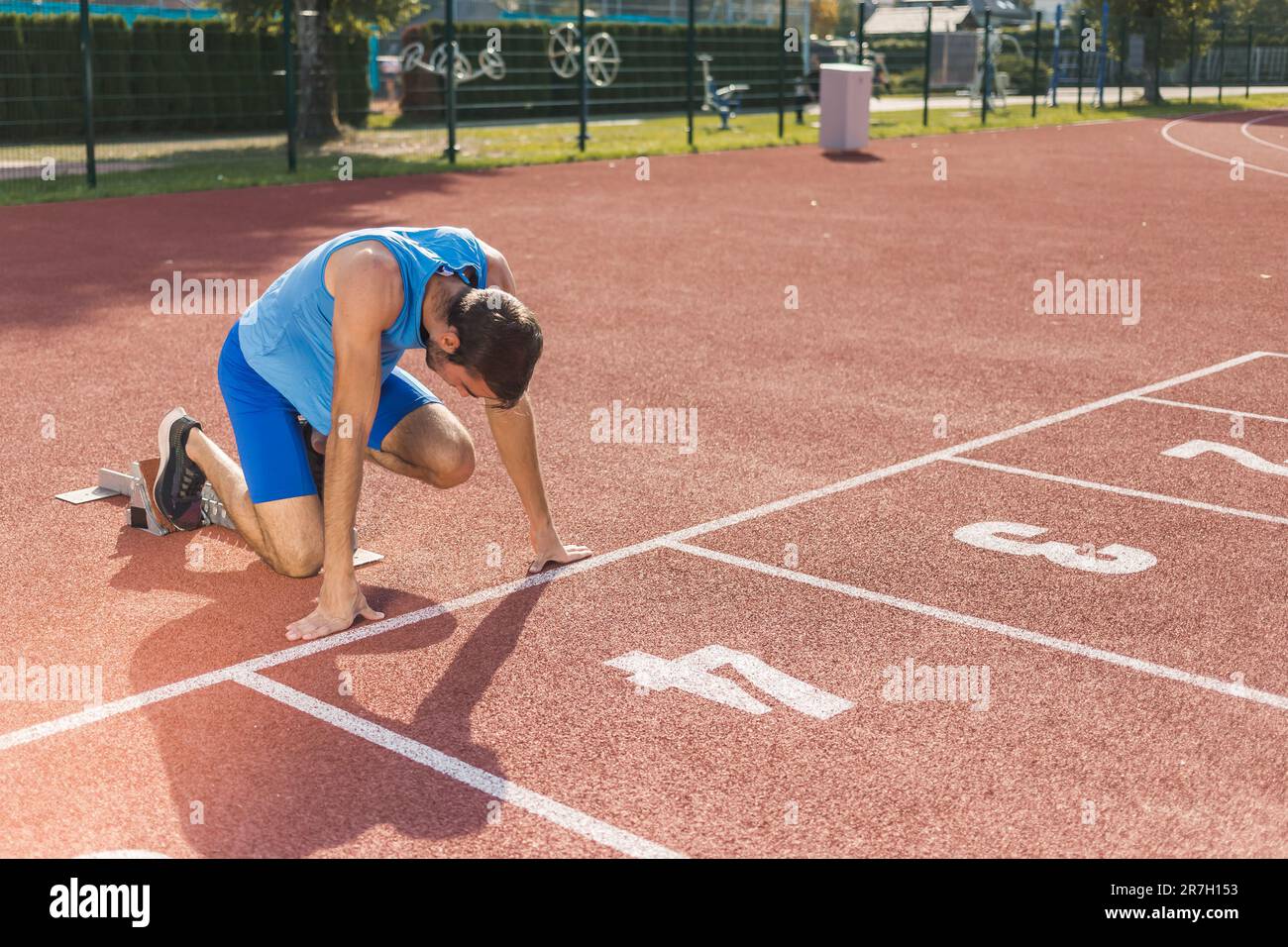 Young professional male athlete in blue sportswear taking a start ...