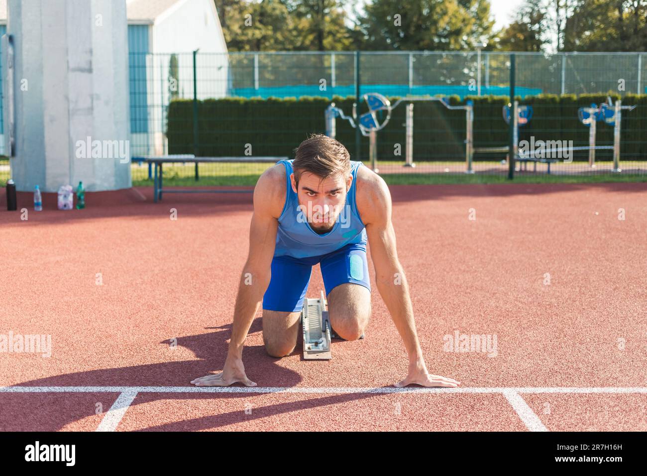 Front view of a Caucasian male sprinter in a race starting position ...