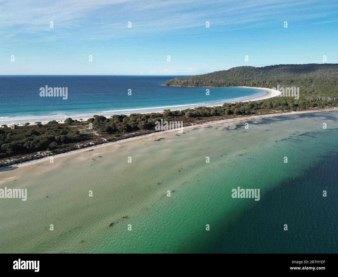 An aerial view of a shoreline, featuring a wide expanse of aquamarine ...