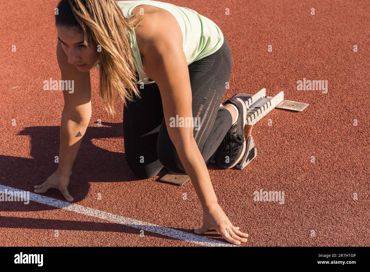 Young female athlete beyond start line, assuming crouching start ...