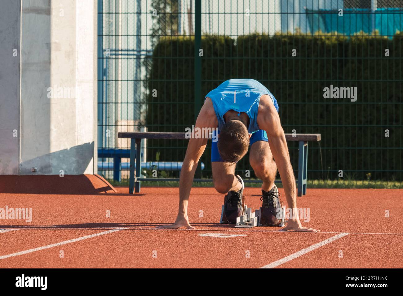 Male Caucasian sprinter assuming a starting position in the starting ...