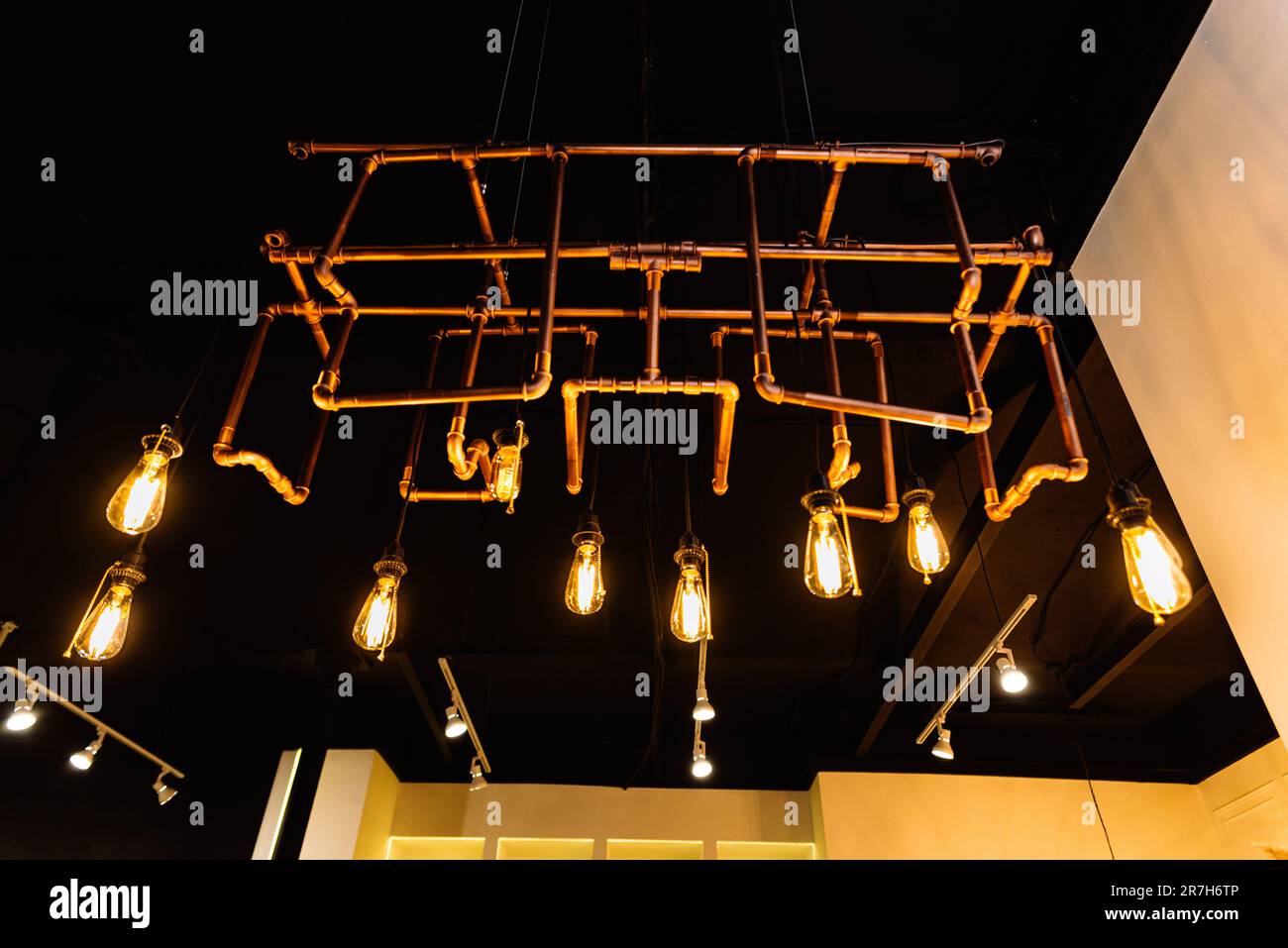 Ceiling light bulbs on copper pipes decorate the interior of the dark ...