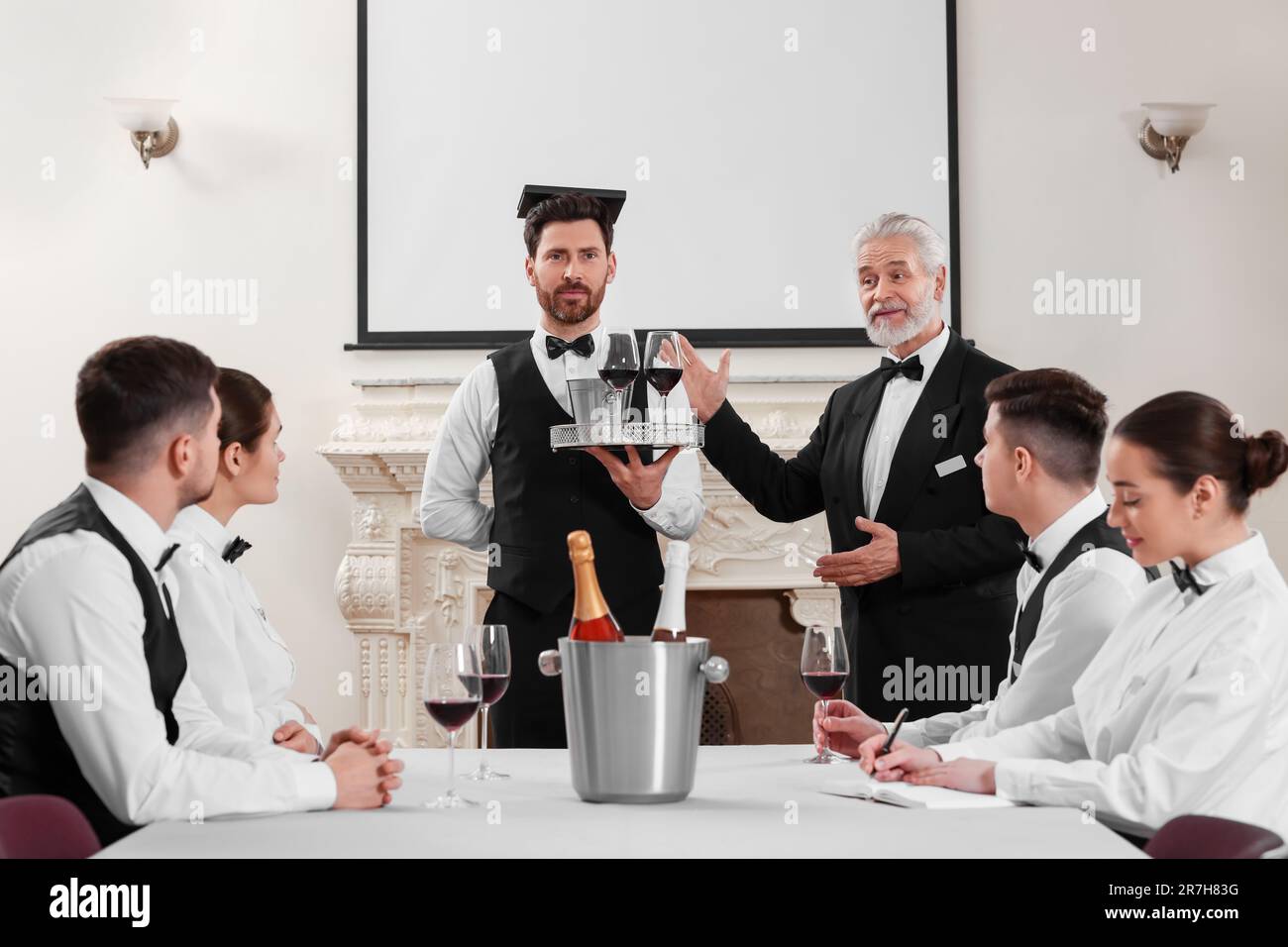 Senior man in formal suit teaching trainees indoors. Professional ...