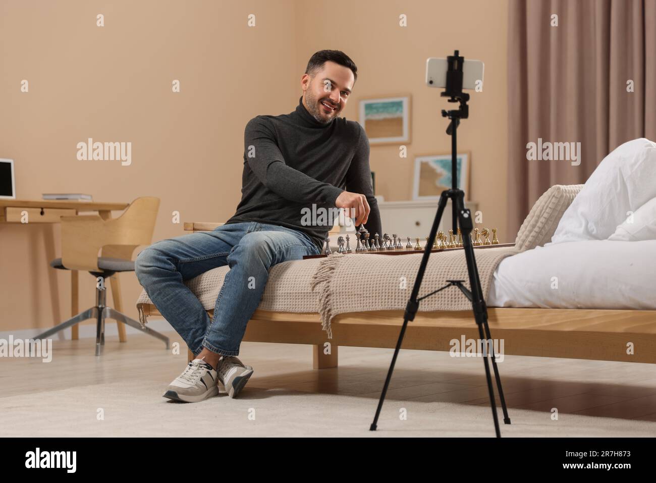 Teacher near chessboard conducting online lesson at home. Time for ...