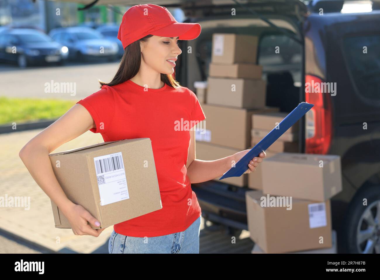 Courier with parcel and clipboard near delivery van outdoors Stock ...